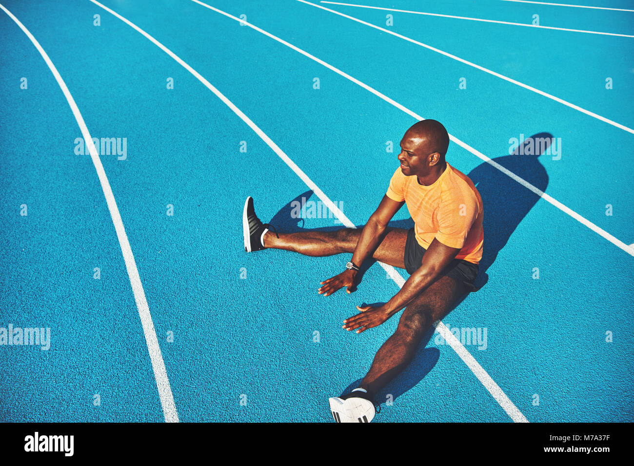 Focused young African male athlete in sportswear sitting alone on the ...