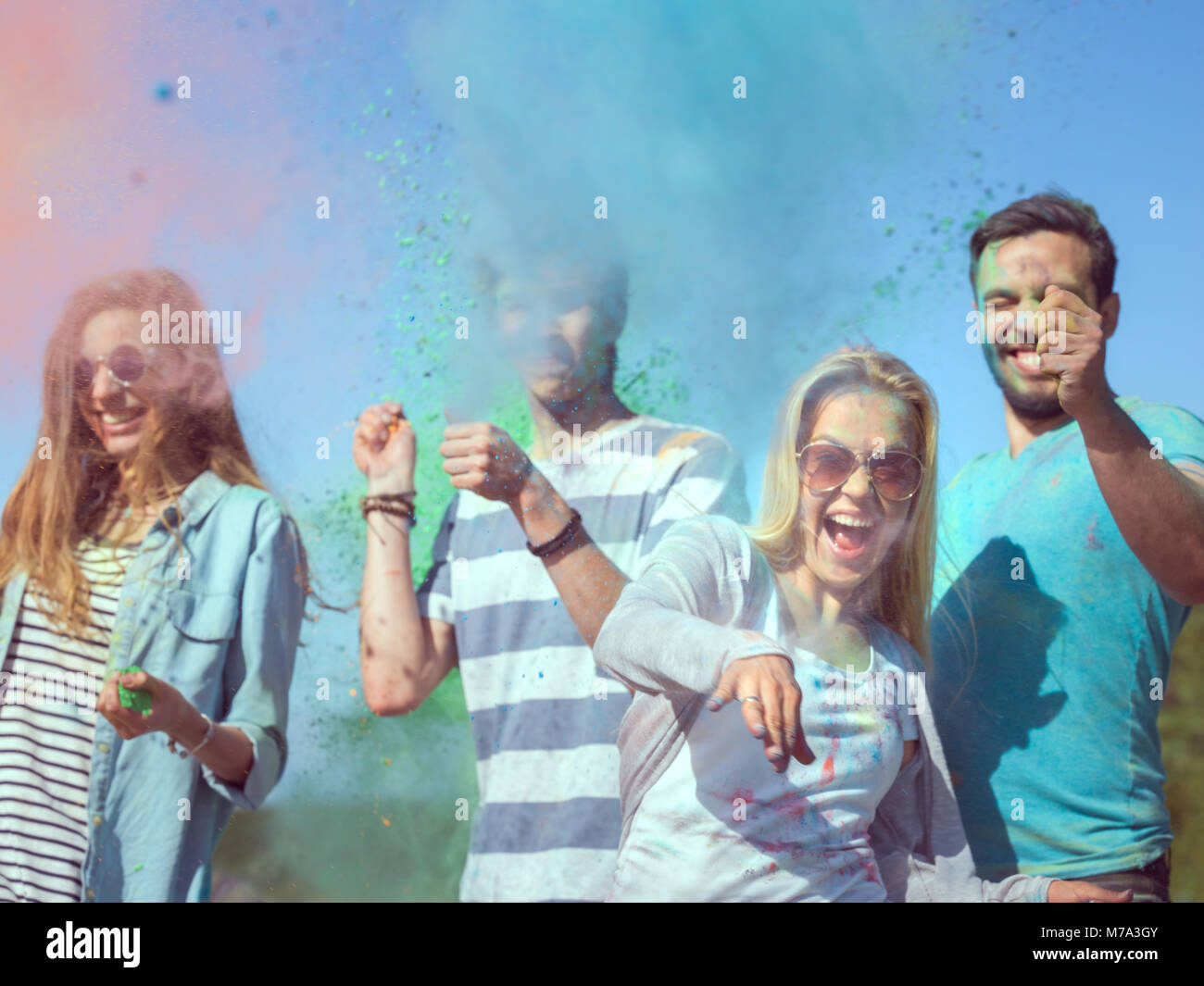 Multi-Ethnic Group of Young People Throw Colorful Powder at Each other ...