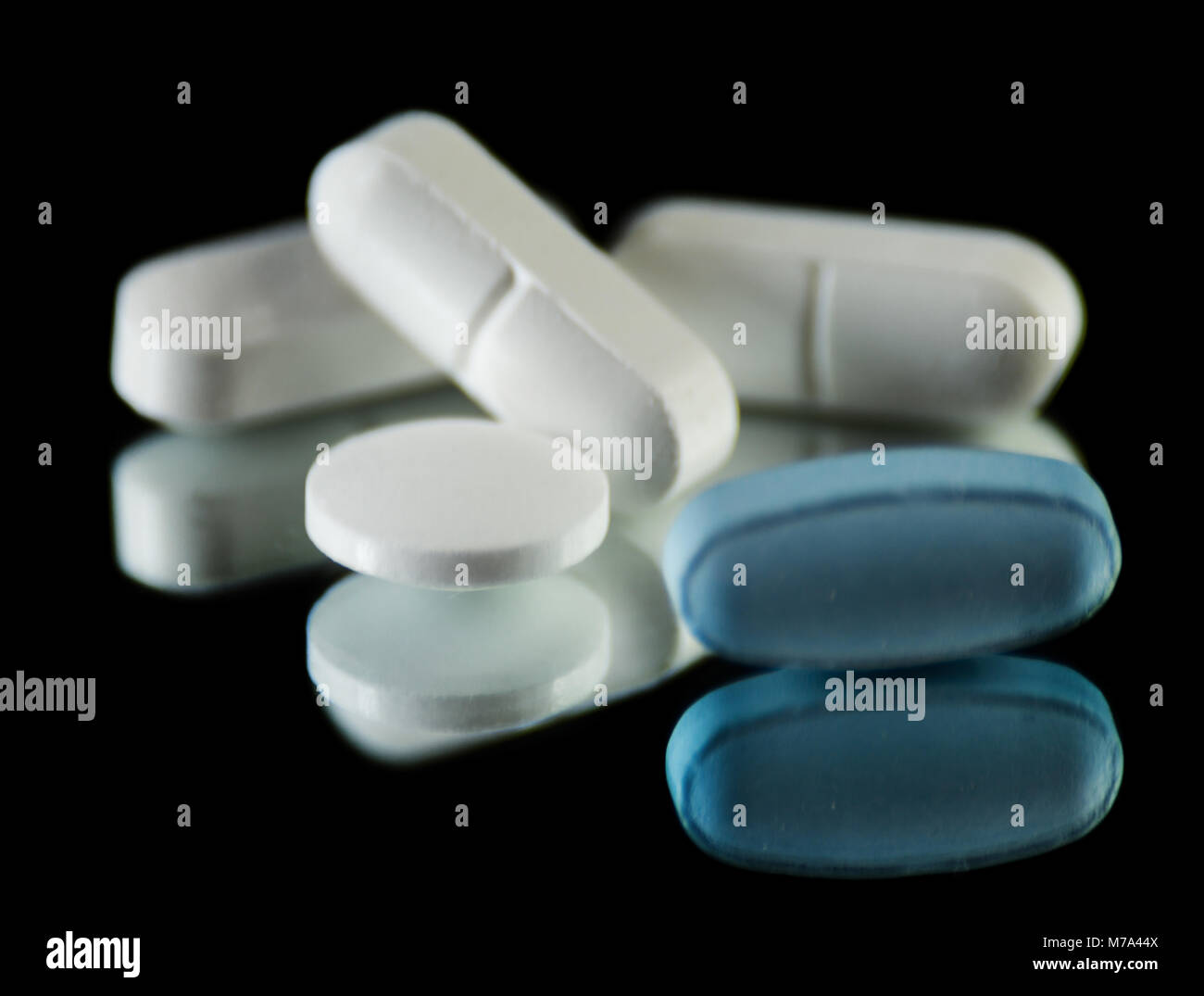 scattered tablets on a black background, pills reflected in the mirror ...