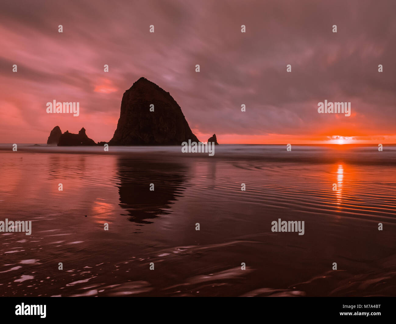Sunset on the Oregon coast. Haystack Rock silhouette reflects in the ...