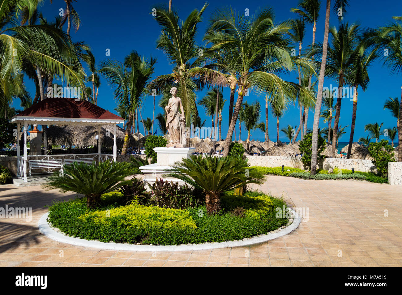 A Greek style statue and shelter are located amongst the palm trees, on ...