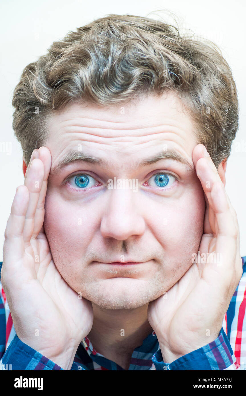 Portrait of young Caucasian Ethnicity blue-eyed man covers his face ...