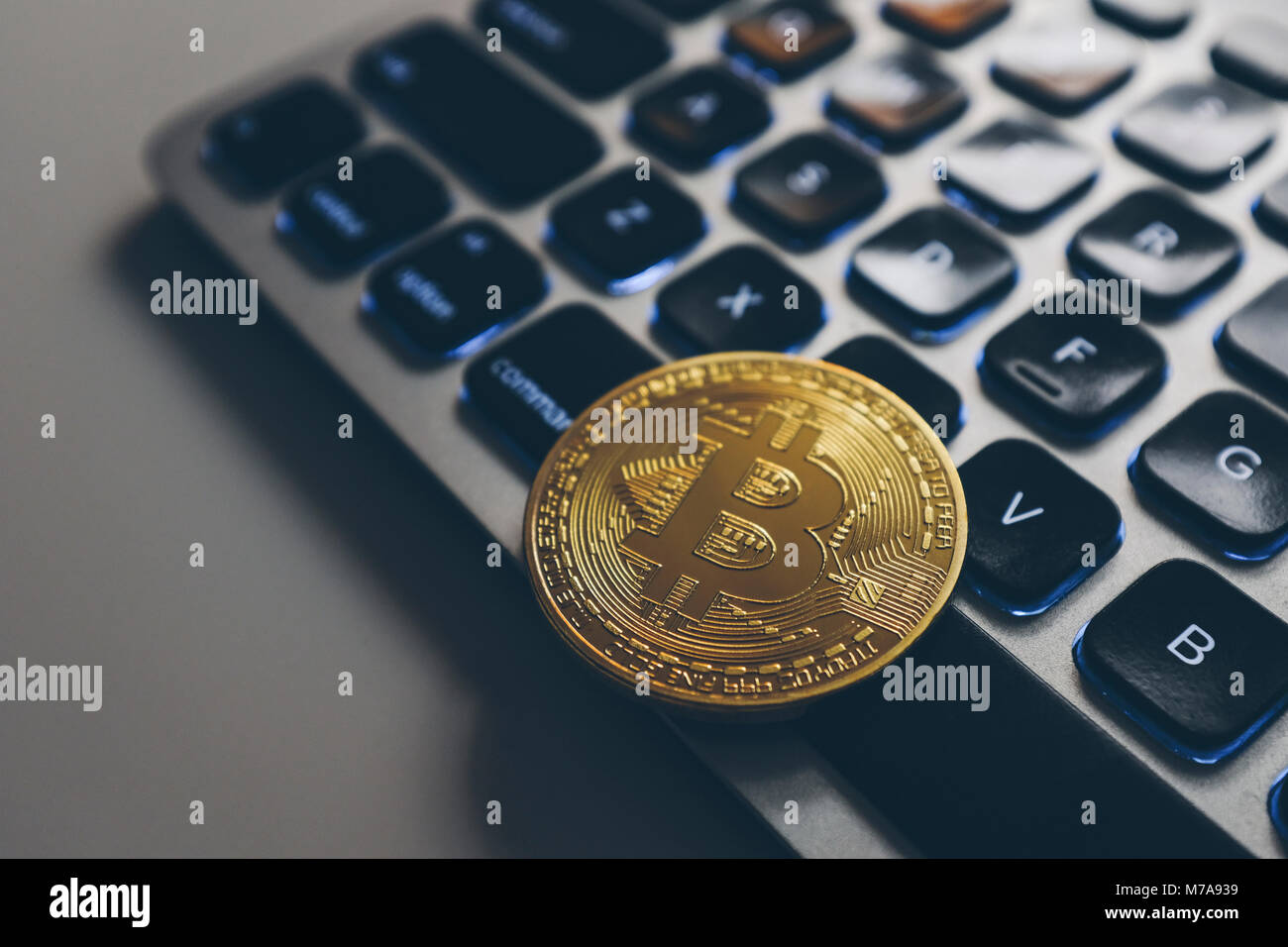 Bitcoin gold coin on computer keyboard backlit Stock Photo - Alamy