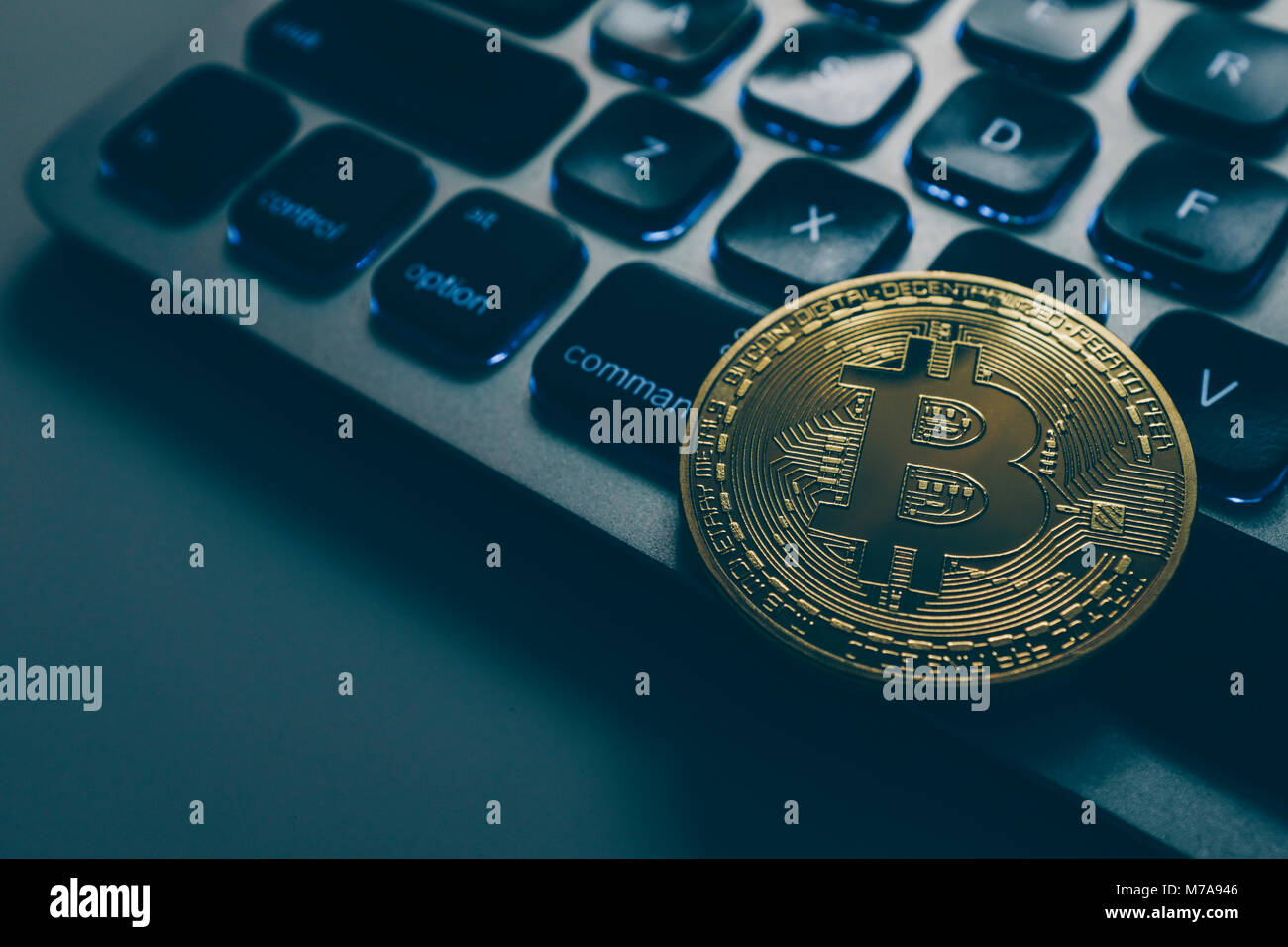 Bitcoin gold coin on computer keyboard backlit Stock Photo - Alamy