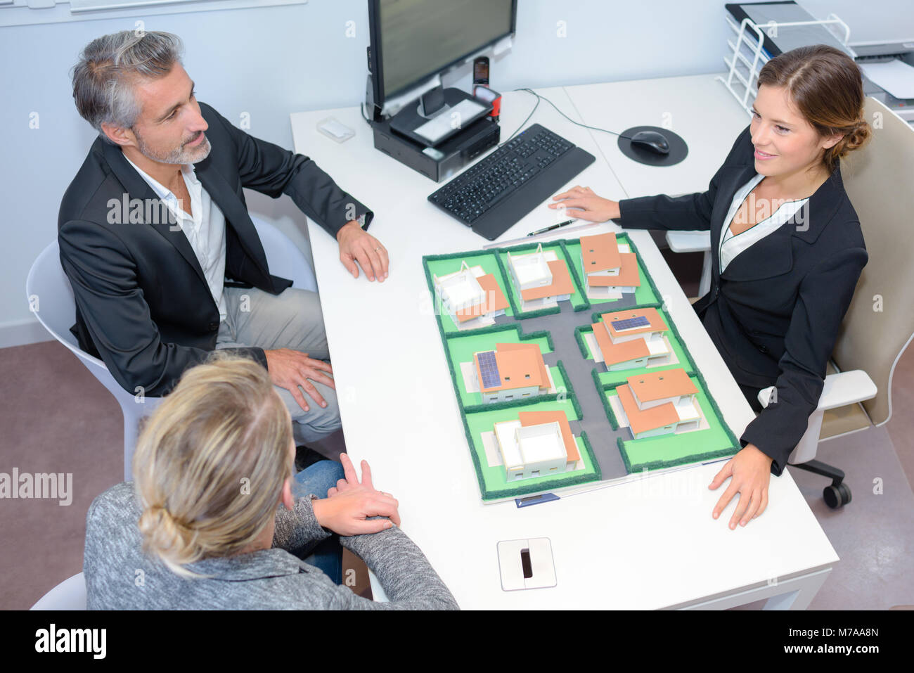 Architect looking at model development with couple Stock Photo - Alamy