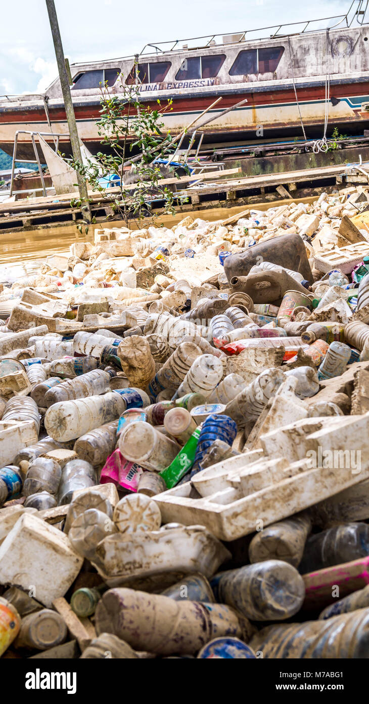 stack of plastic garbage floating in the river with boat as the ...