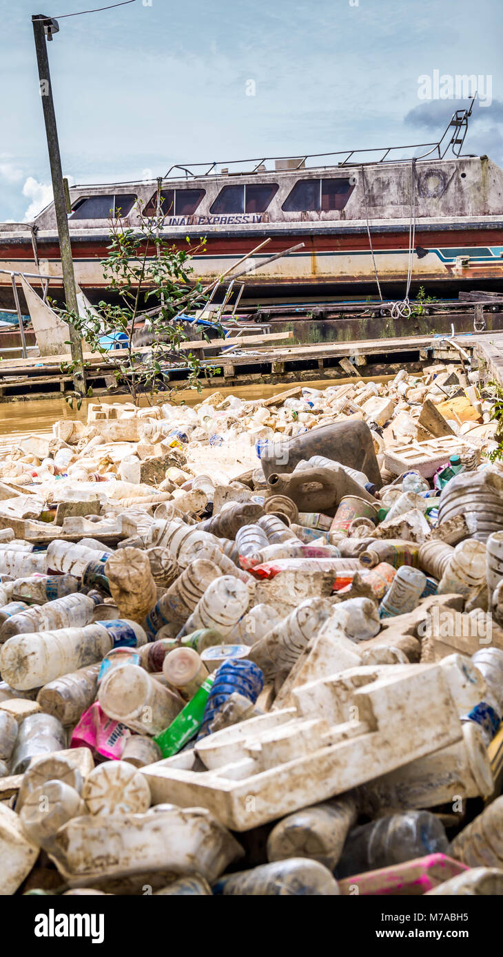 stack of plastic garbage floating in the river with boat as the ...