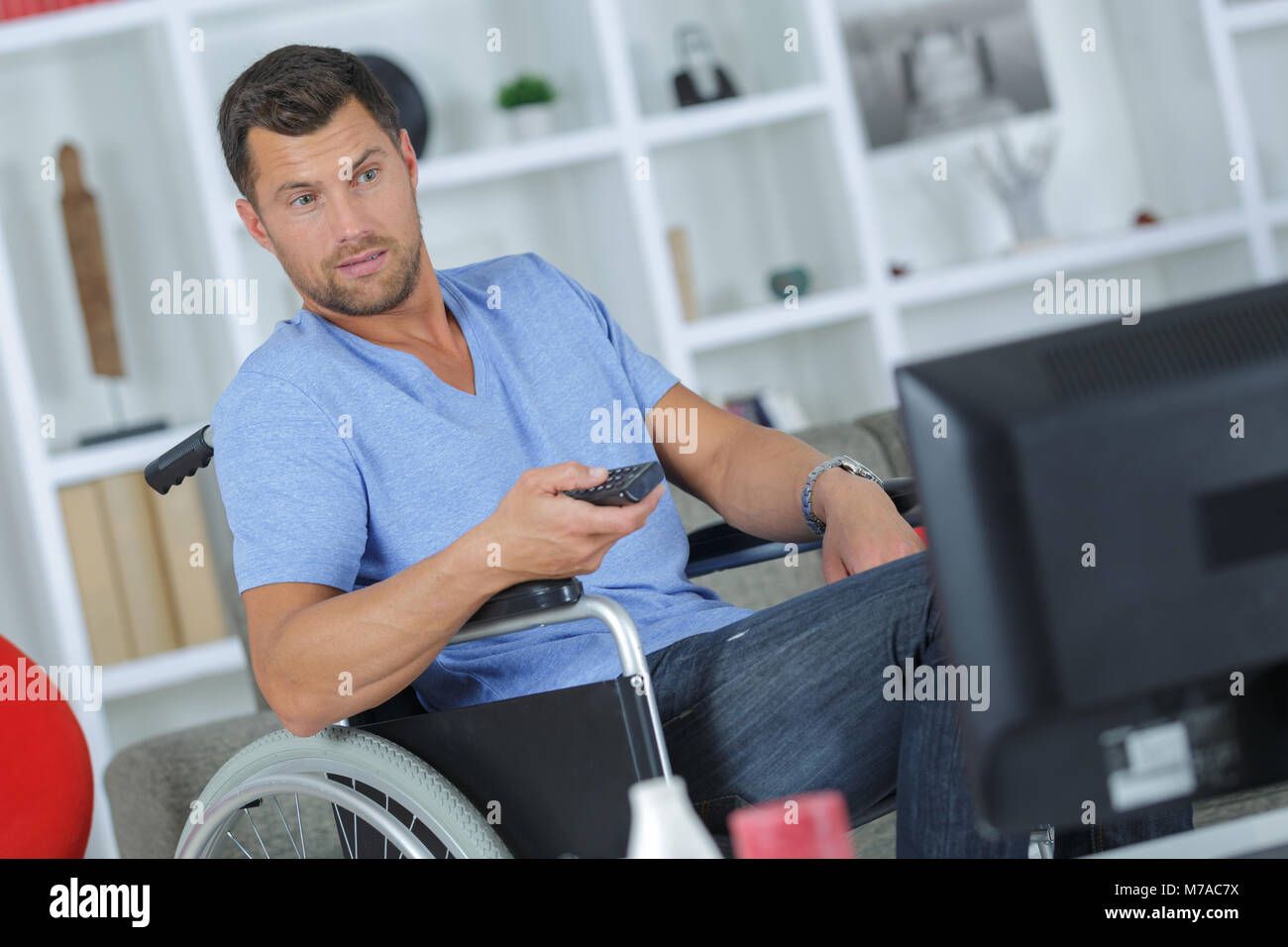 man on the wheelchair holding a remote control Stock Photo - Alamy