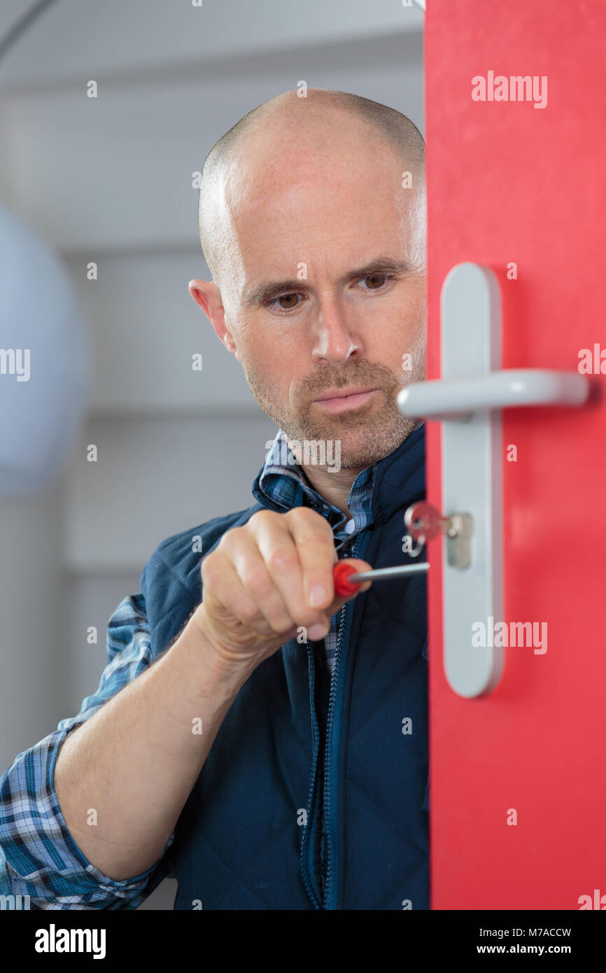 male carpenter fixing lock in door Stock Photo - Alamy