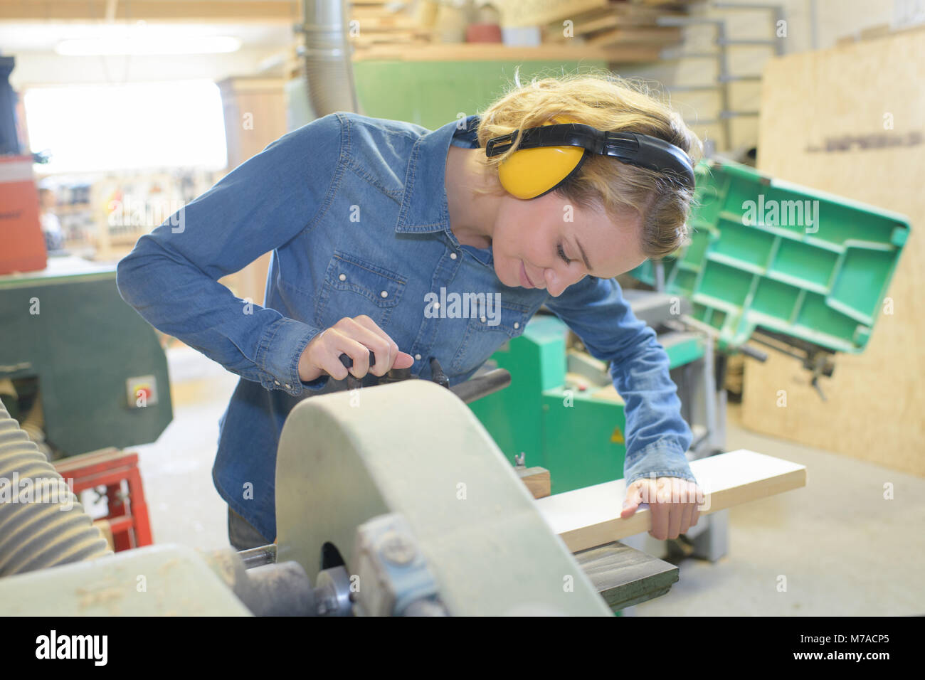 happy female carpenter using machine on wood in workshop Stock Photo ...