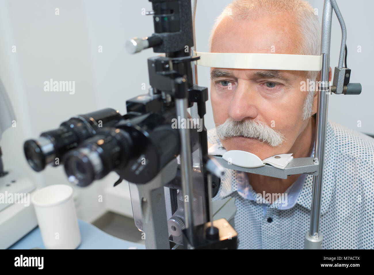 senior man looking into slit lamp at clinic Stock Photo - Alamy