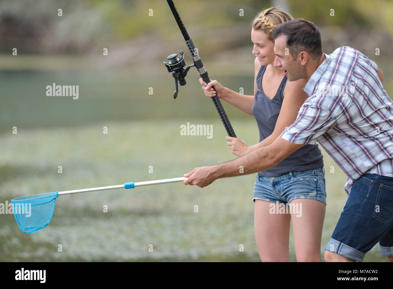 man with fishing rod showing girlfriend how to fish Stock Photo - Alamy