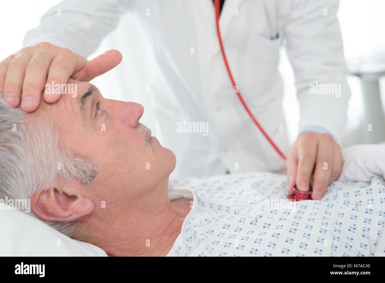 Doctor feeling forehead of patient while listening to his heart Stock ...