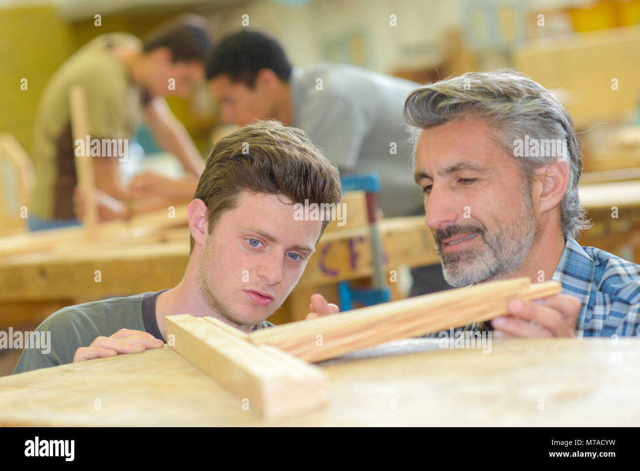 Carpenter looking at his apprentice's work Stock Photo - Alamy