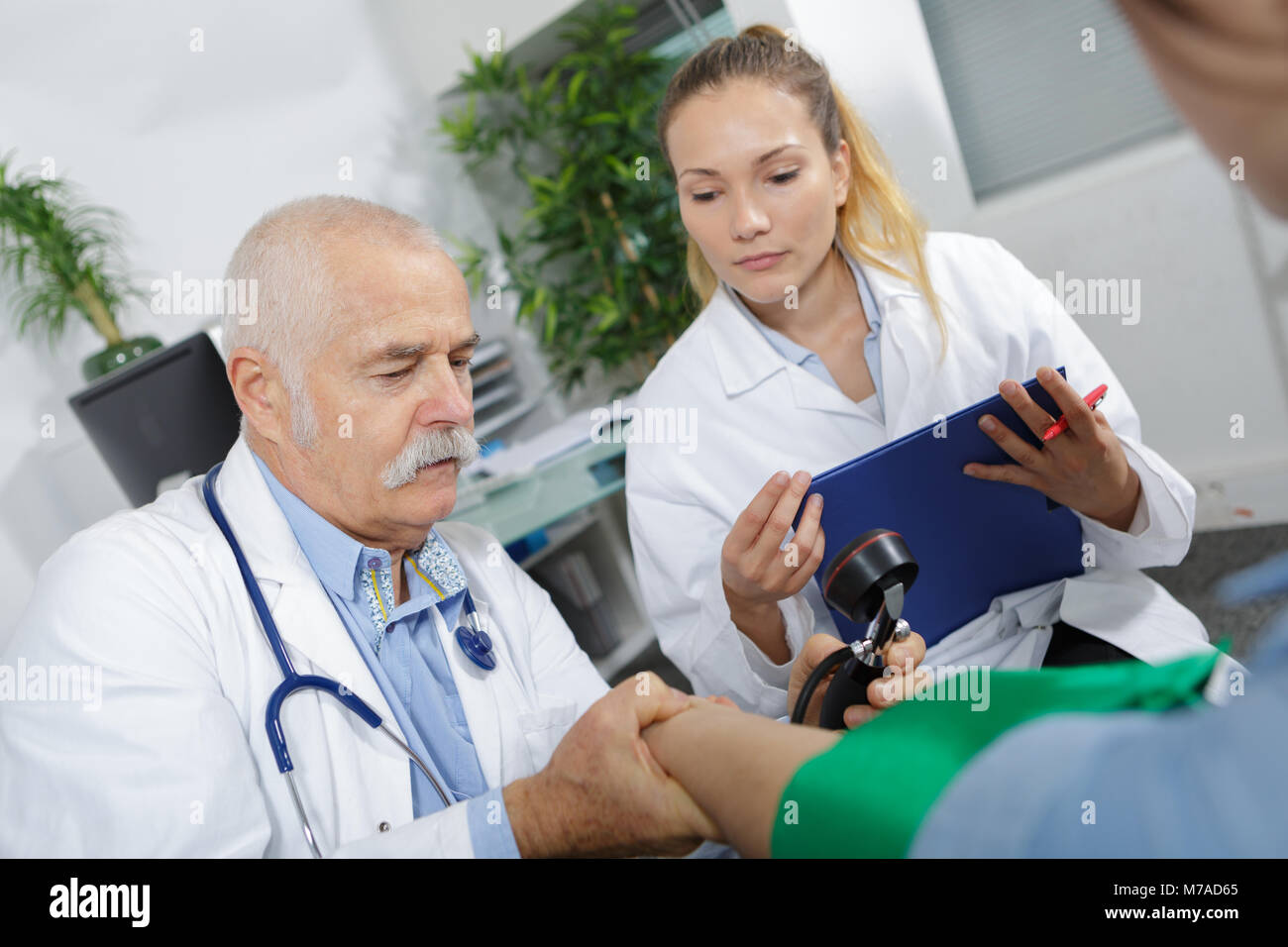 doctor measuring patients blood pressure with stethoscope Stock Photo ...
