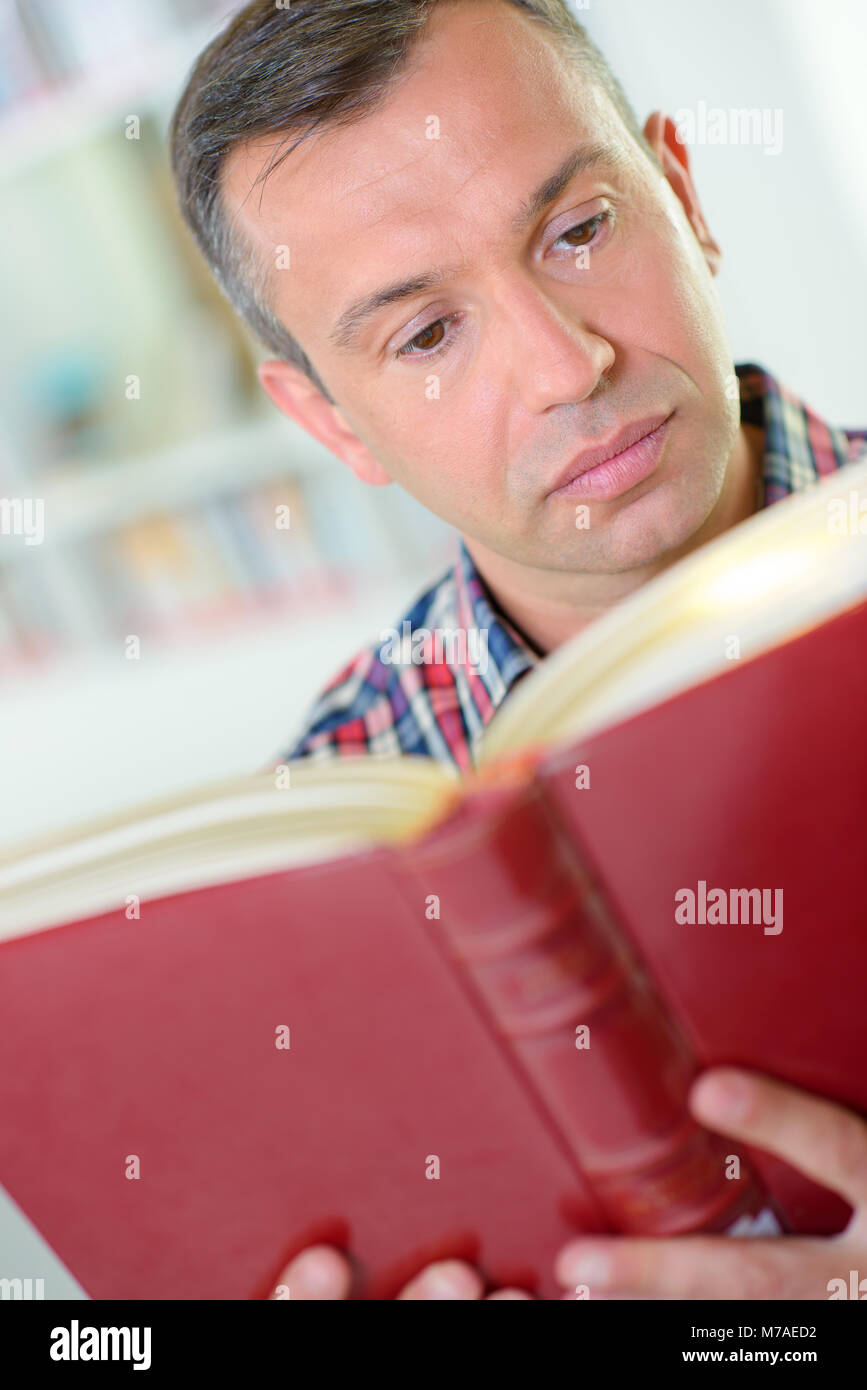 man reading a red book Stock Photo - Alamy
