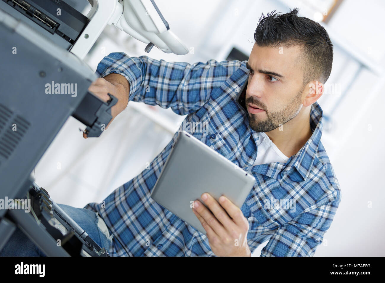 technician using a tablet to fix a printer Stock Photo - Alamy