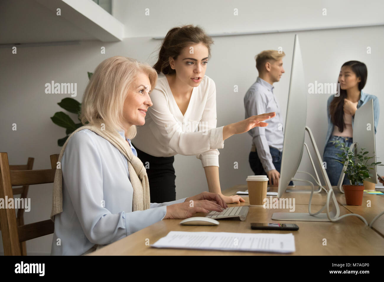Young businesswoman teaching smiling senior colleague explaining Stock ...