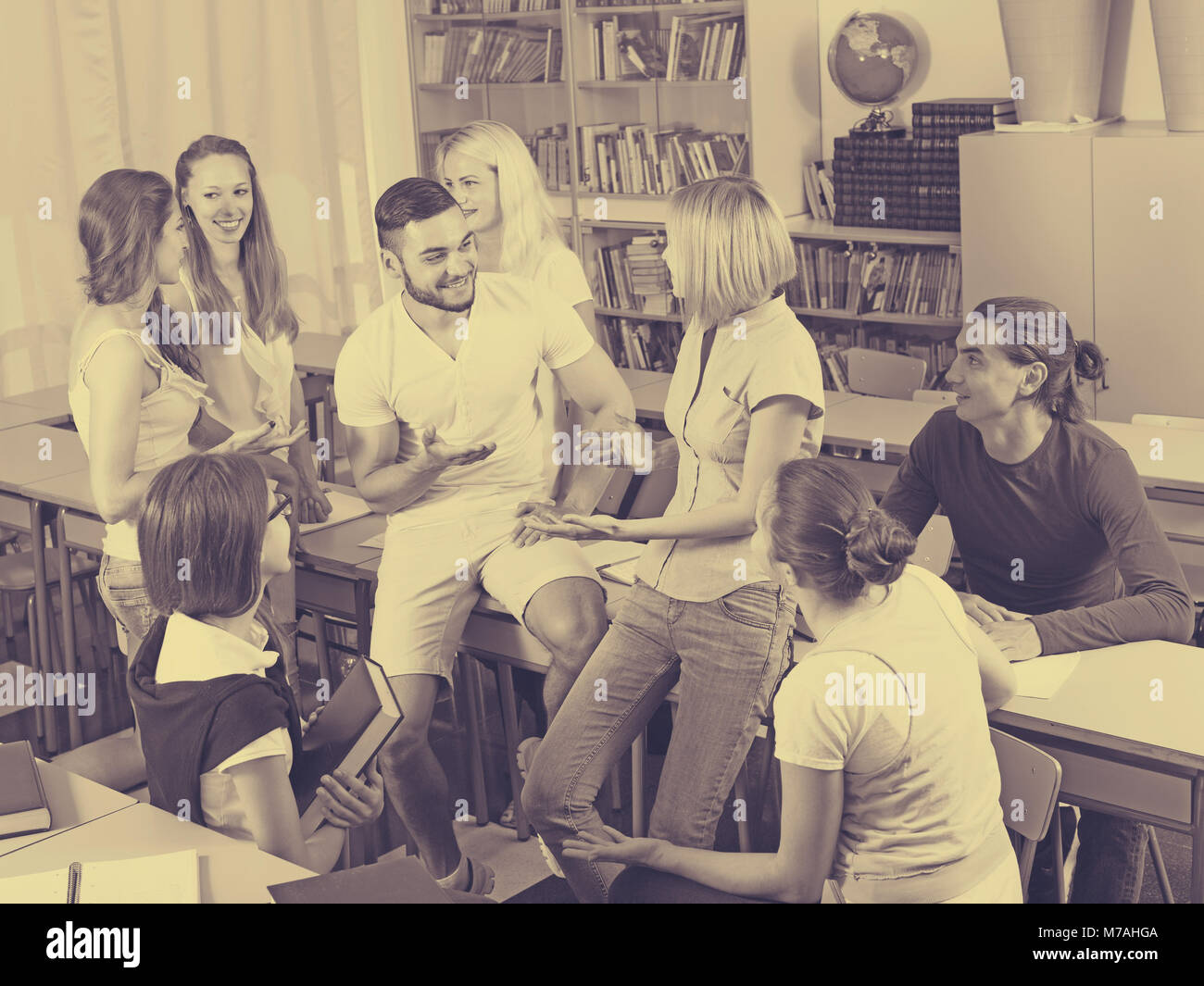 Happy young students during break in classroom interior Stock Photo - Alamy