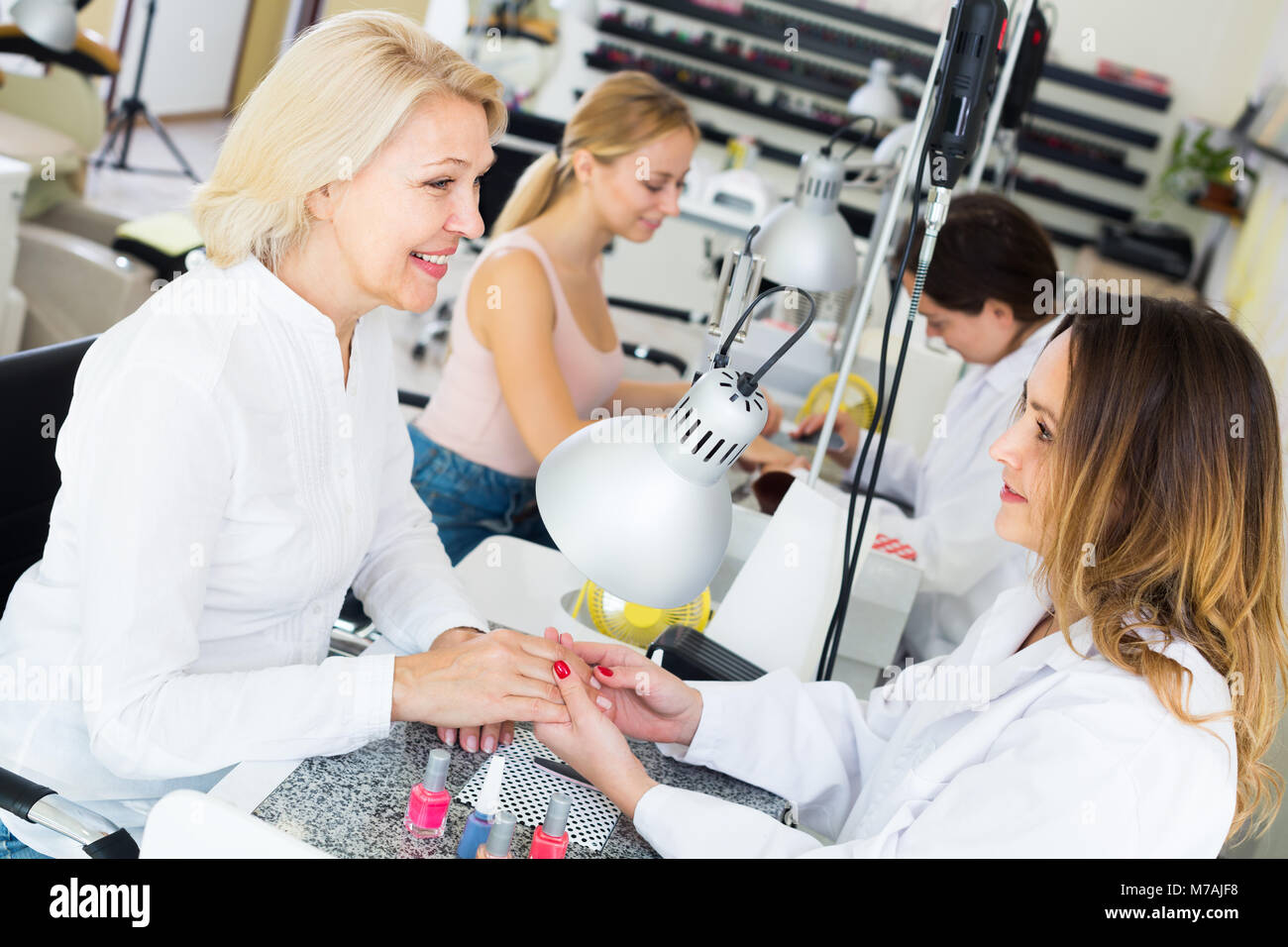 Two cheerful clients doing manicure in nail salon Stock Photo - Alamy