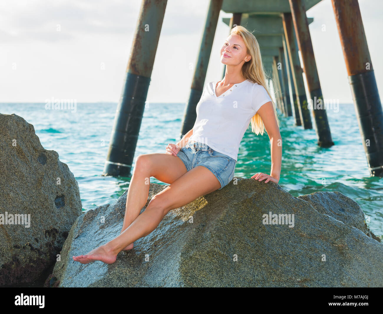 Female is posing on the rocks in her free time near ocean Stock Photo ...