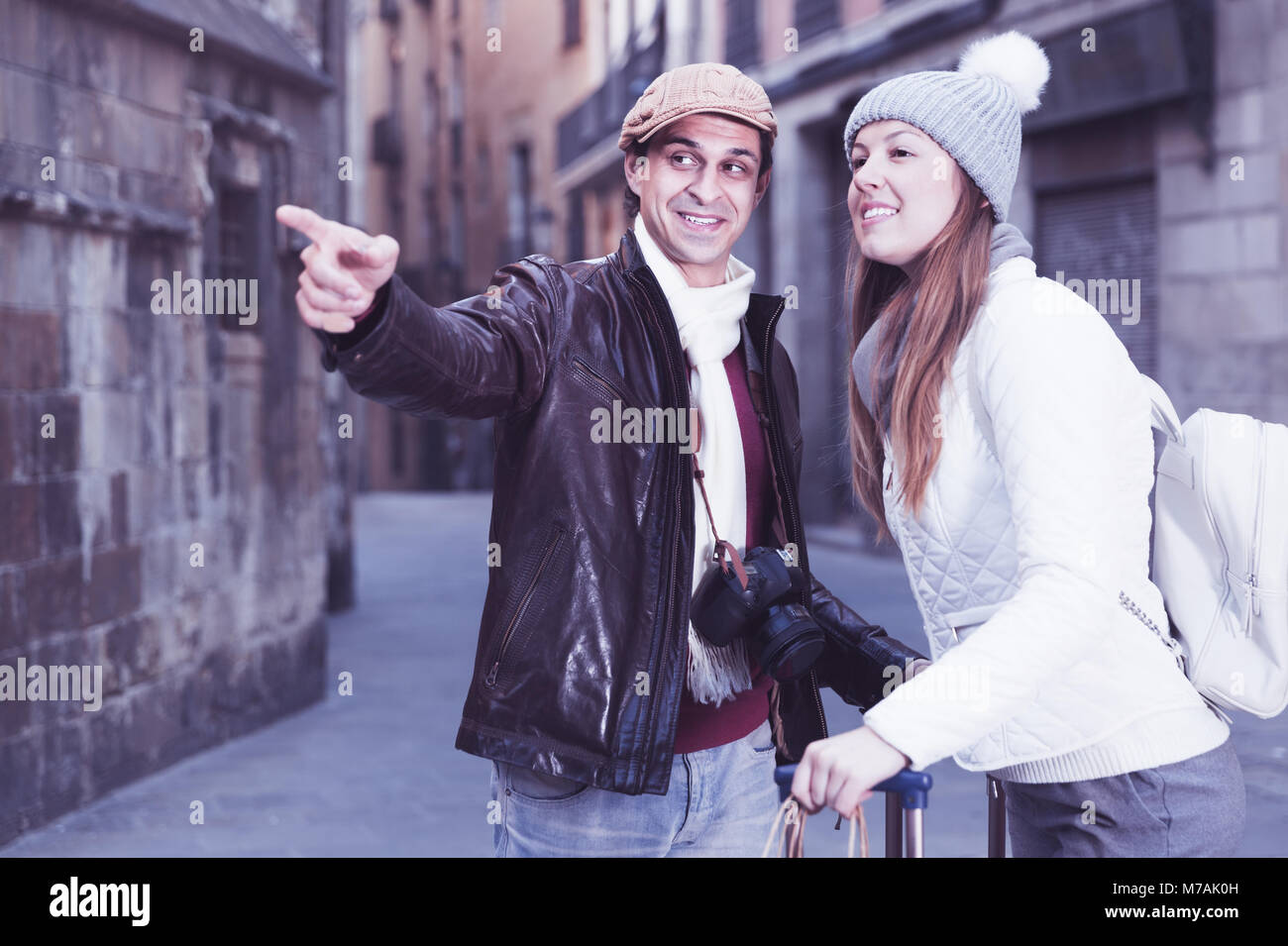 Cheerful adult travelers in hats and scarfs pointing finger on ...
