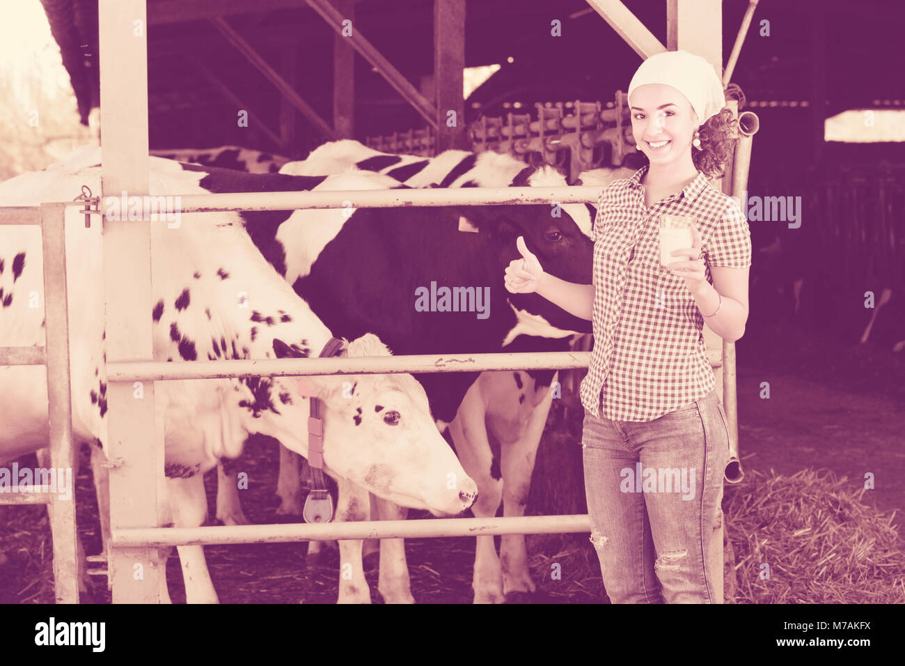Portrait of happy smiling female farm workers holding glass with milk ...