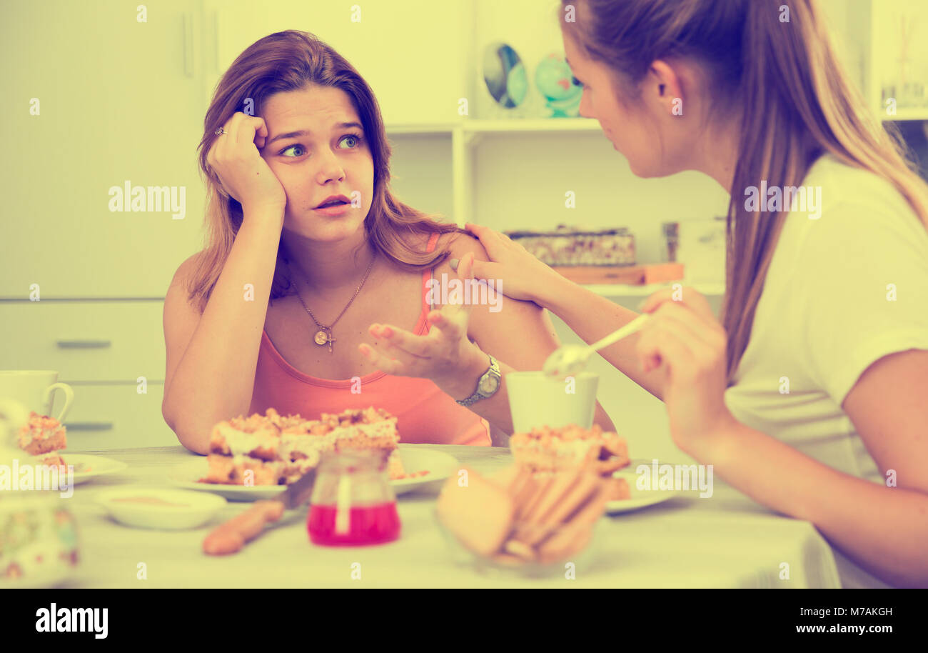 Portrait of female talking with sad girl friend at the kitchen Stock ...