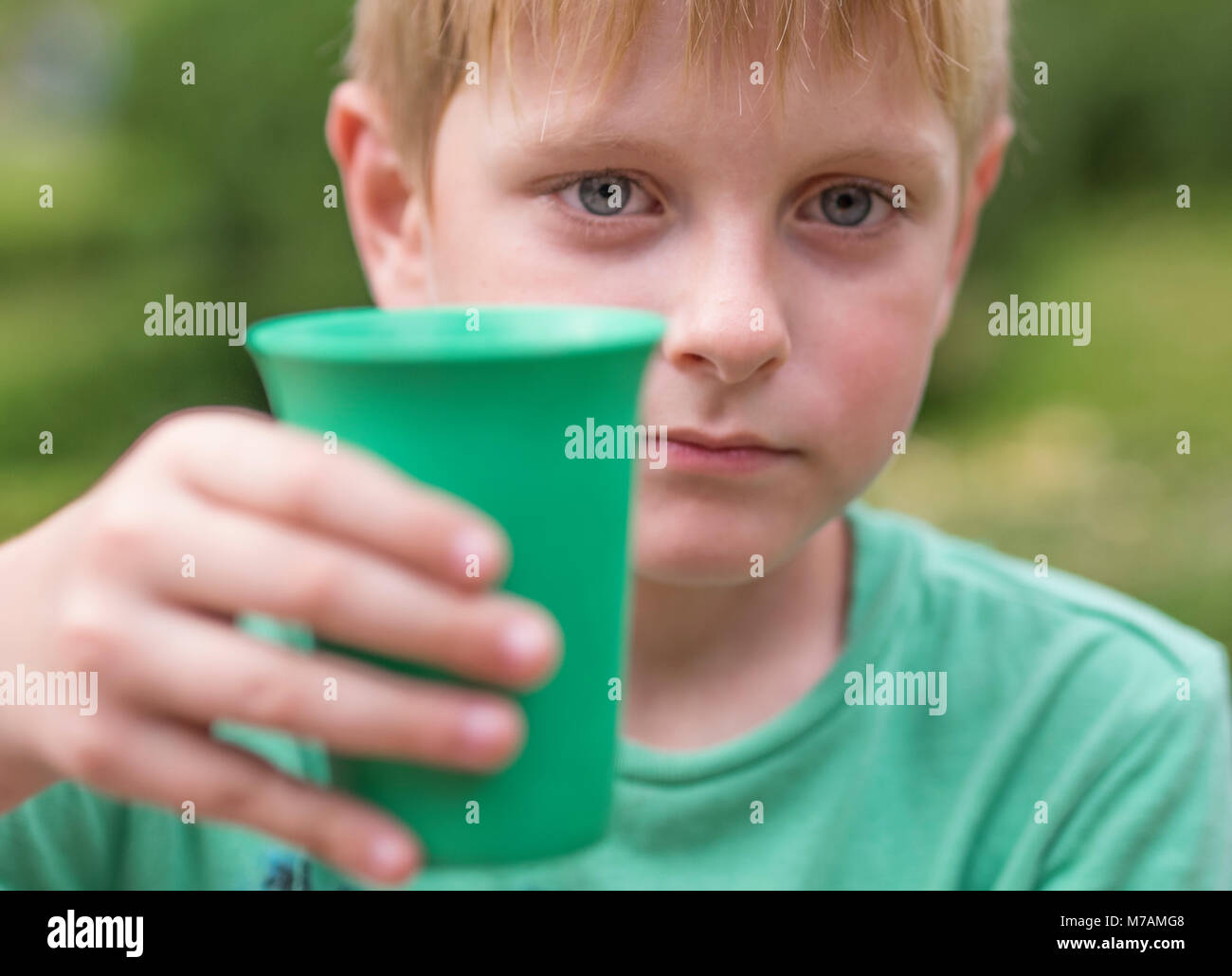 Caucasian boy holding a green plastic cup and looking at camera Stock ...