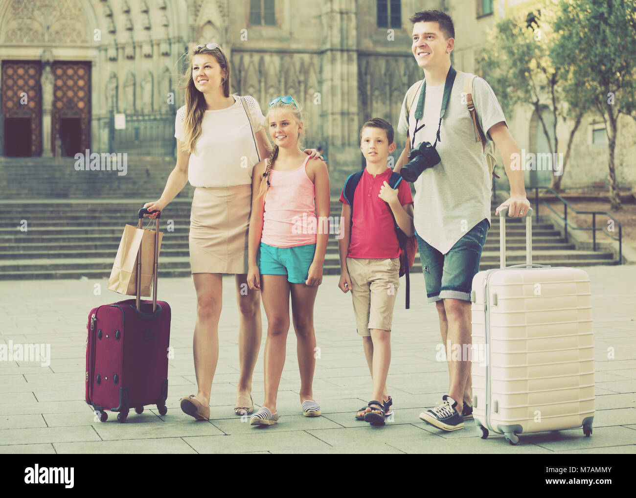 Positive family with children travelling together on city, walking with ...