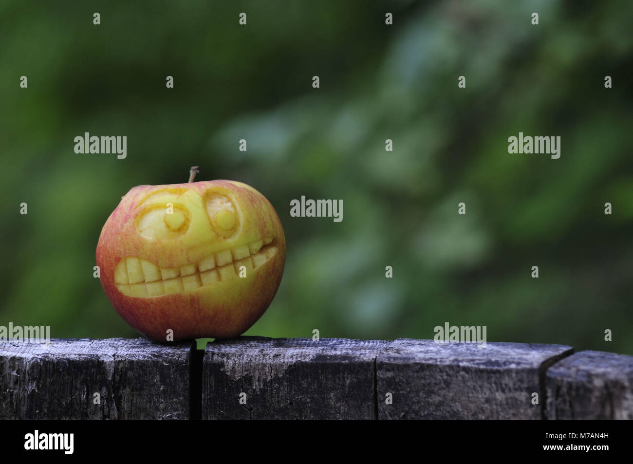 Apple with carved face in front of blurred background, close up Stock ...