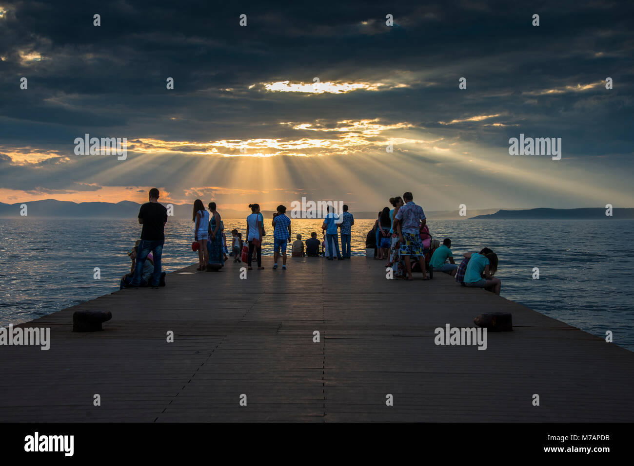 Tourists watching the sun breaking through the clouds above the Amur in ...