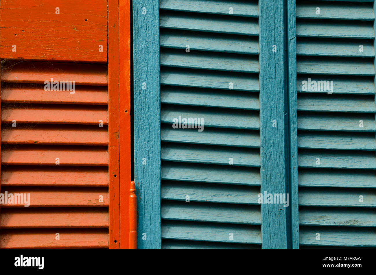 Abstract close up of orange and blue textured wooden window shutters ...