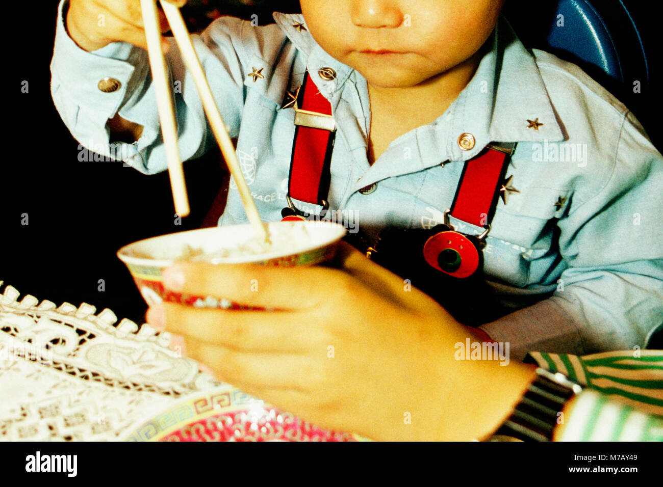 Close-up of a boy learning from his father how to use chopsticks, Hong ...