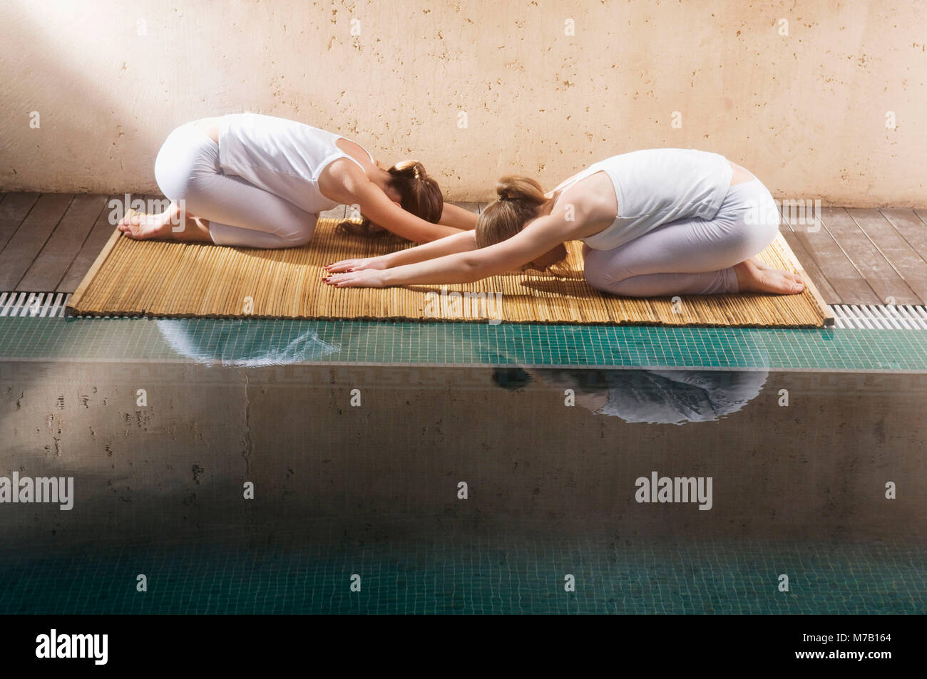 Side profile of two young women exercising at the poolside Stock Photo ...