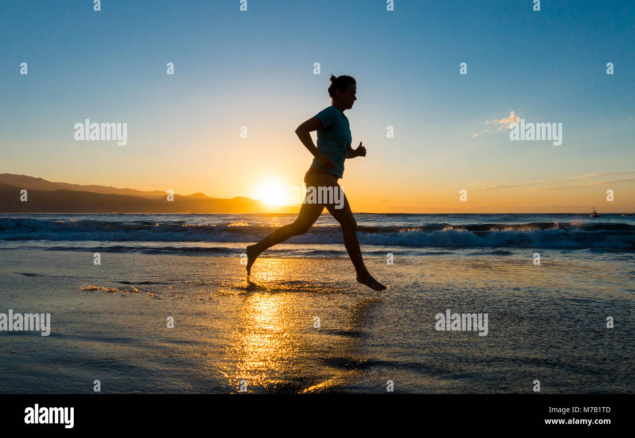 Woman jogging on beach at sunset Stock Photo - Alamy