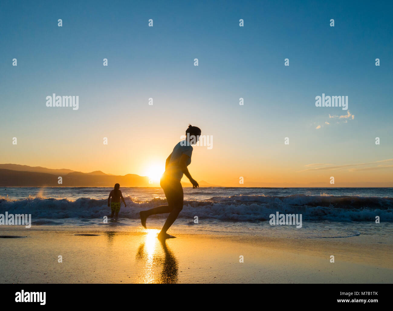 Woman jogging on beach at sunset Stock Photo - Alamy