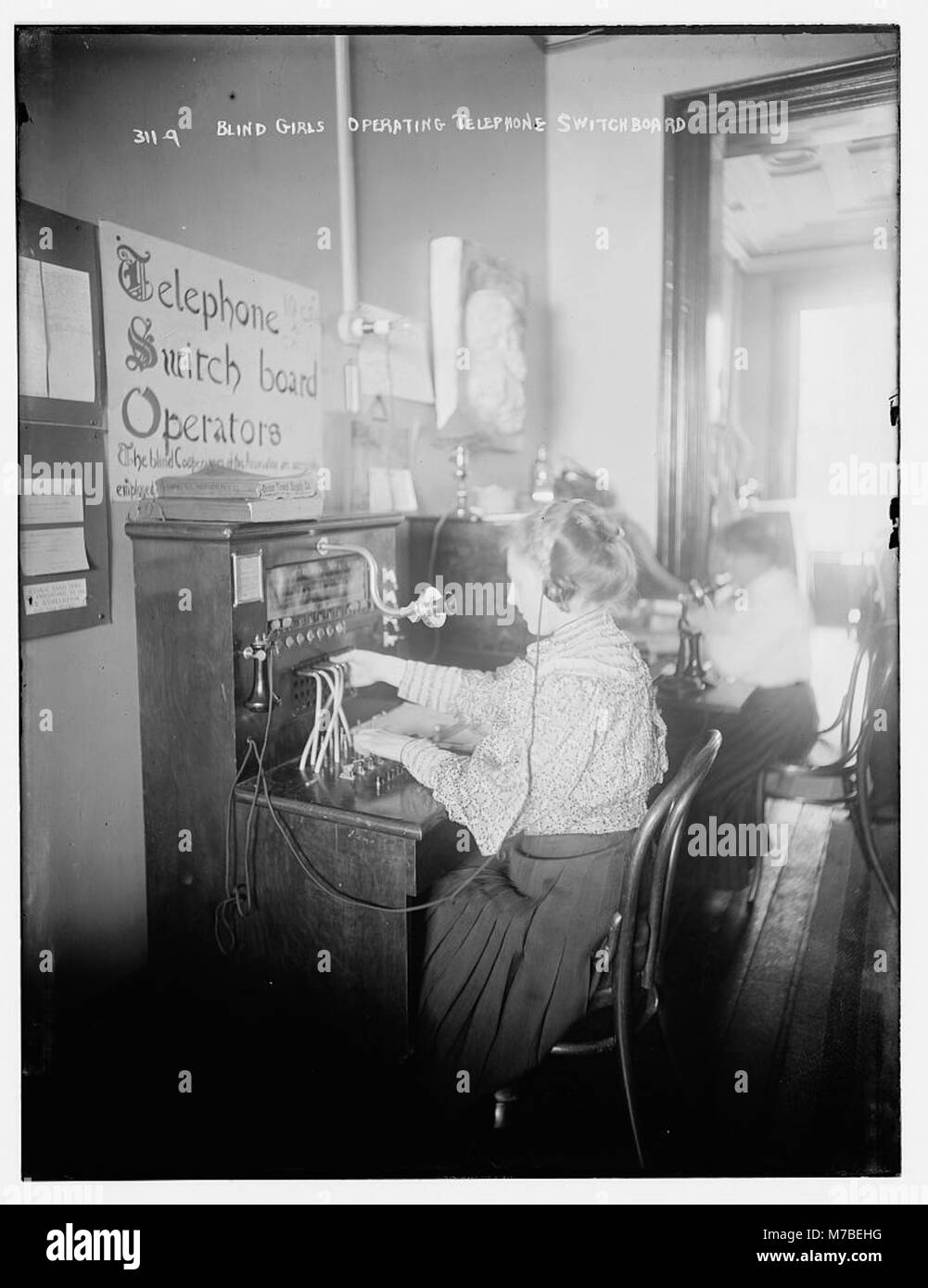 This historical image shows blind girls working at a telephone ...