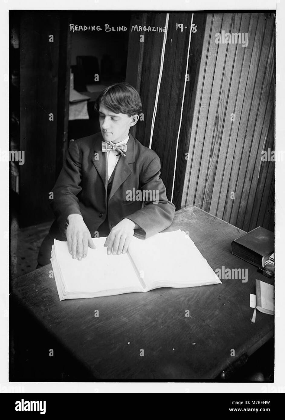 A blind man reading a magazine using tactile methods, representing ...