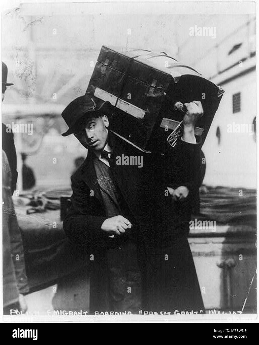 The image depicts a Polish emigrant boarding a ship, carrying a trunk ...