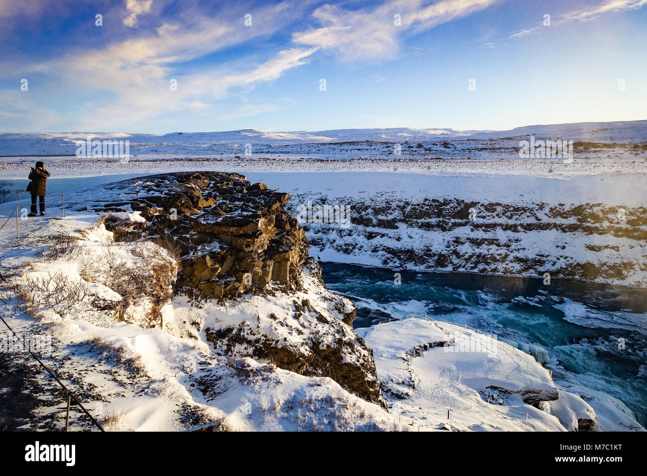 Rear view of person standing on cliff overlooking canyon in Iceland ...