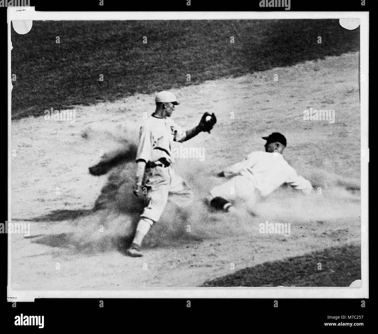 This action shot from a baseball game shows a player sliding into base ...