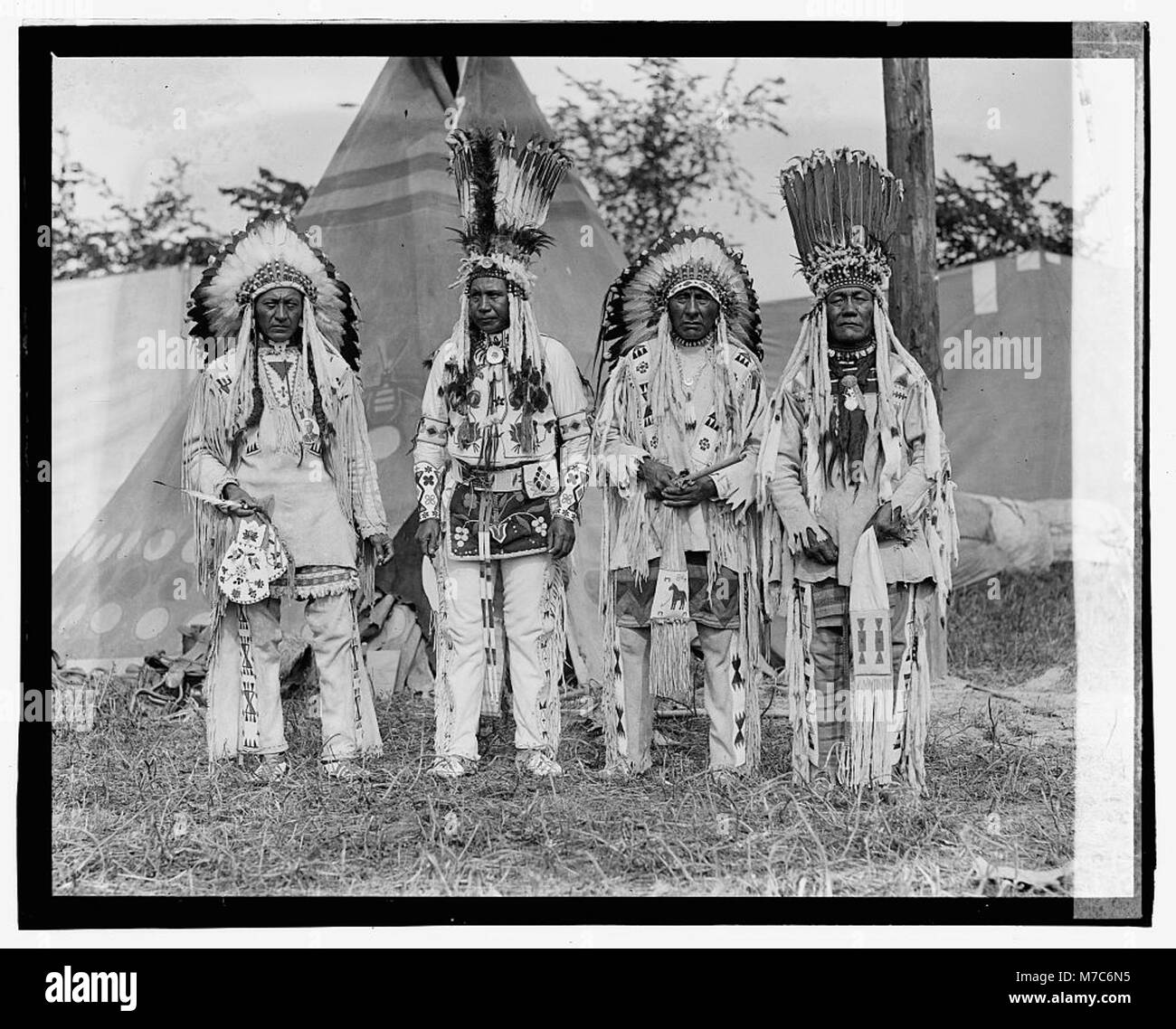 This photograph shows Native Americans dressed in traditional clothing ...