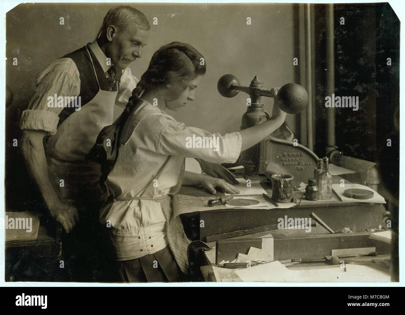 This image shows a 15-year-old girl operating an embossing machine at ...