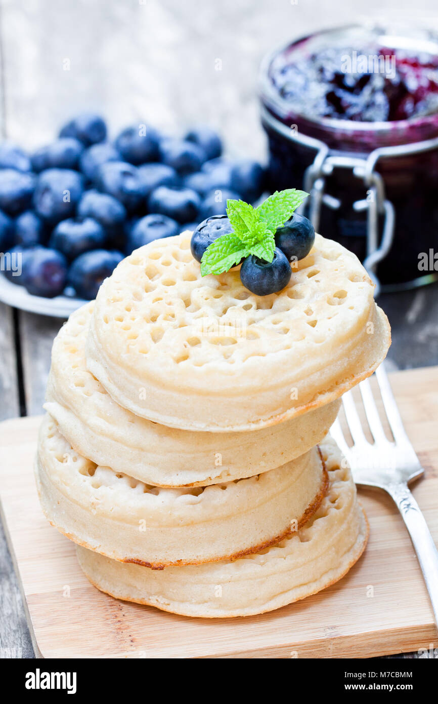 Hot toasted crumpets on the wooden table with blueberries and jam Stock ...