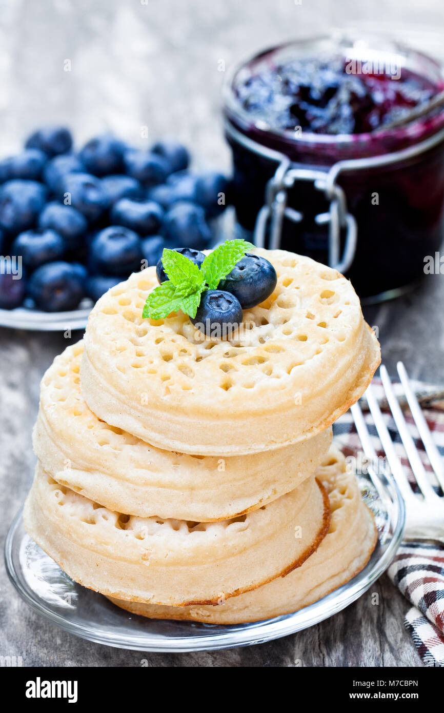 Hot toasted crumpets on the wooden table with blueberries and jam Stock ...