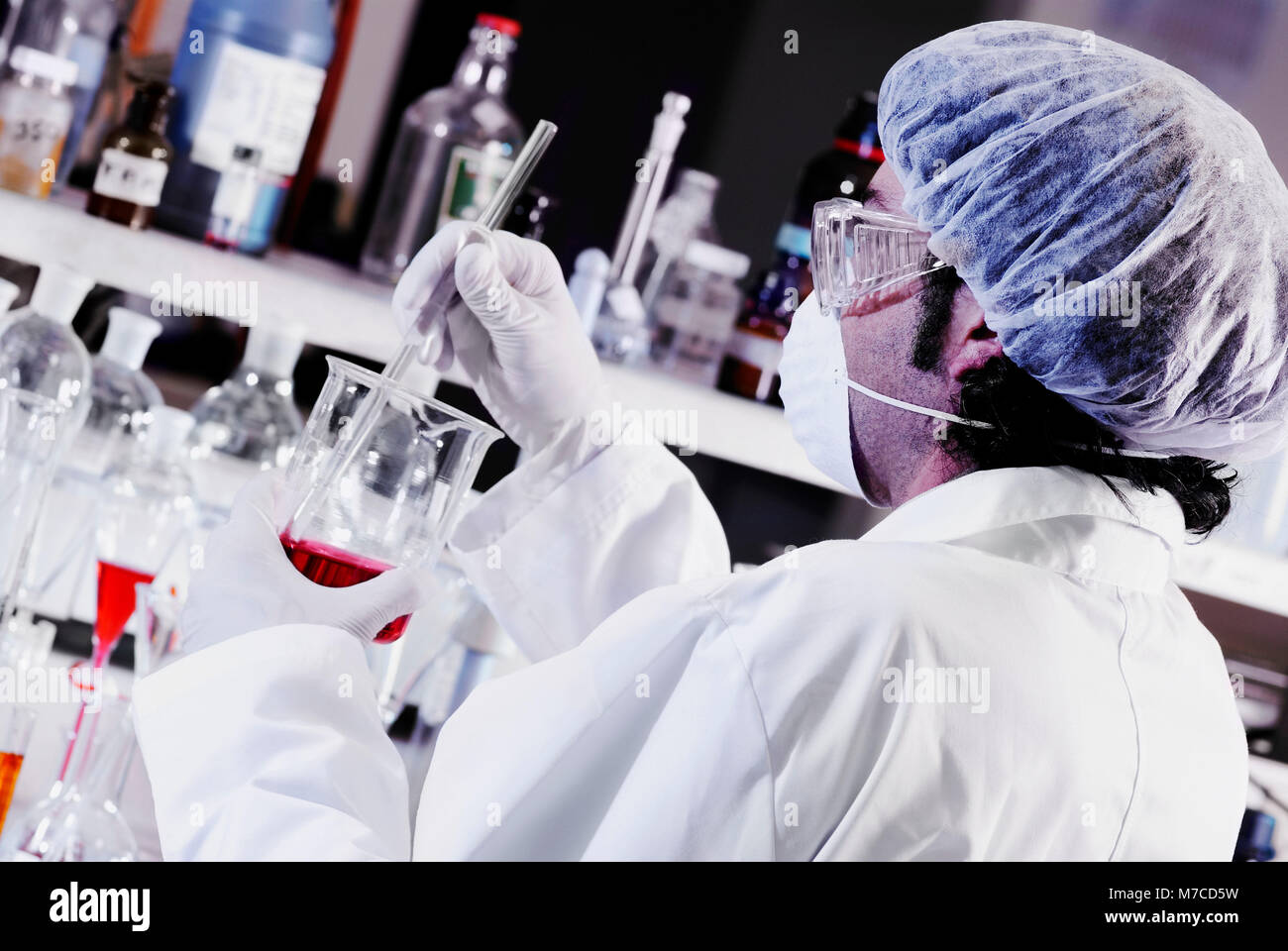 Close-up of a mid adult man stirring liquid in a beaker Stock Photo - Alamy