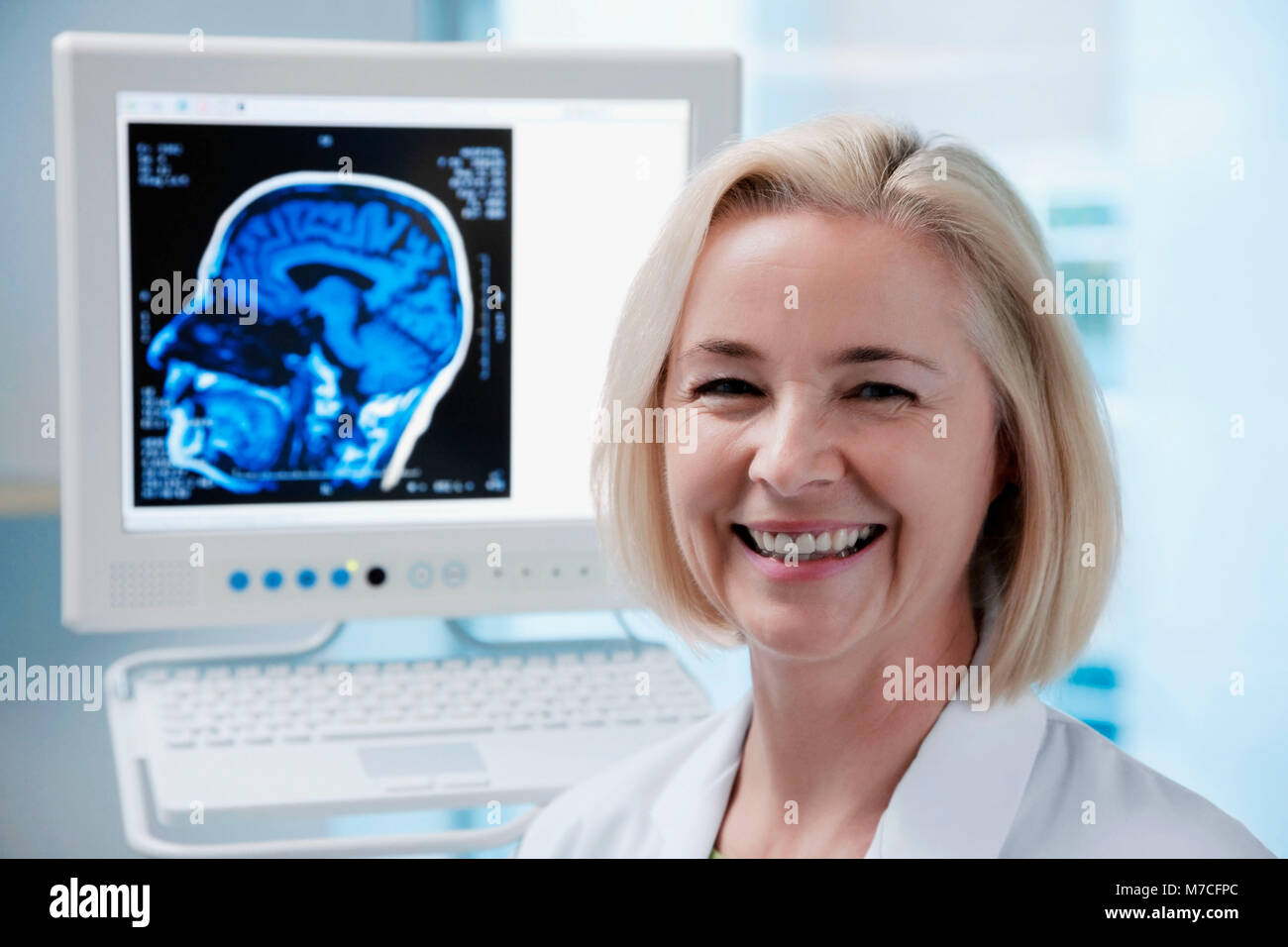 Female doctor smiling with MRI scan of brain on the computer screen ...