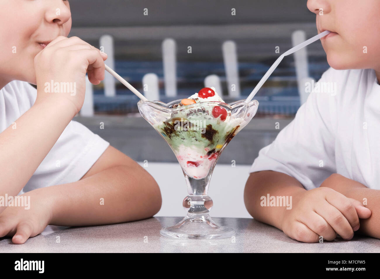 Boy and a girl sharing ice cream in an ice cream parlor Stock Photo - Alamy