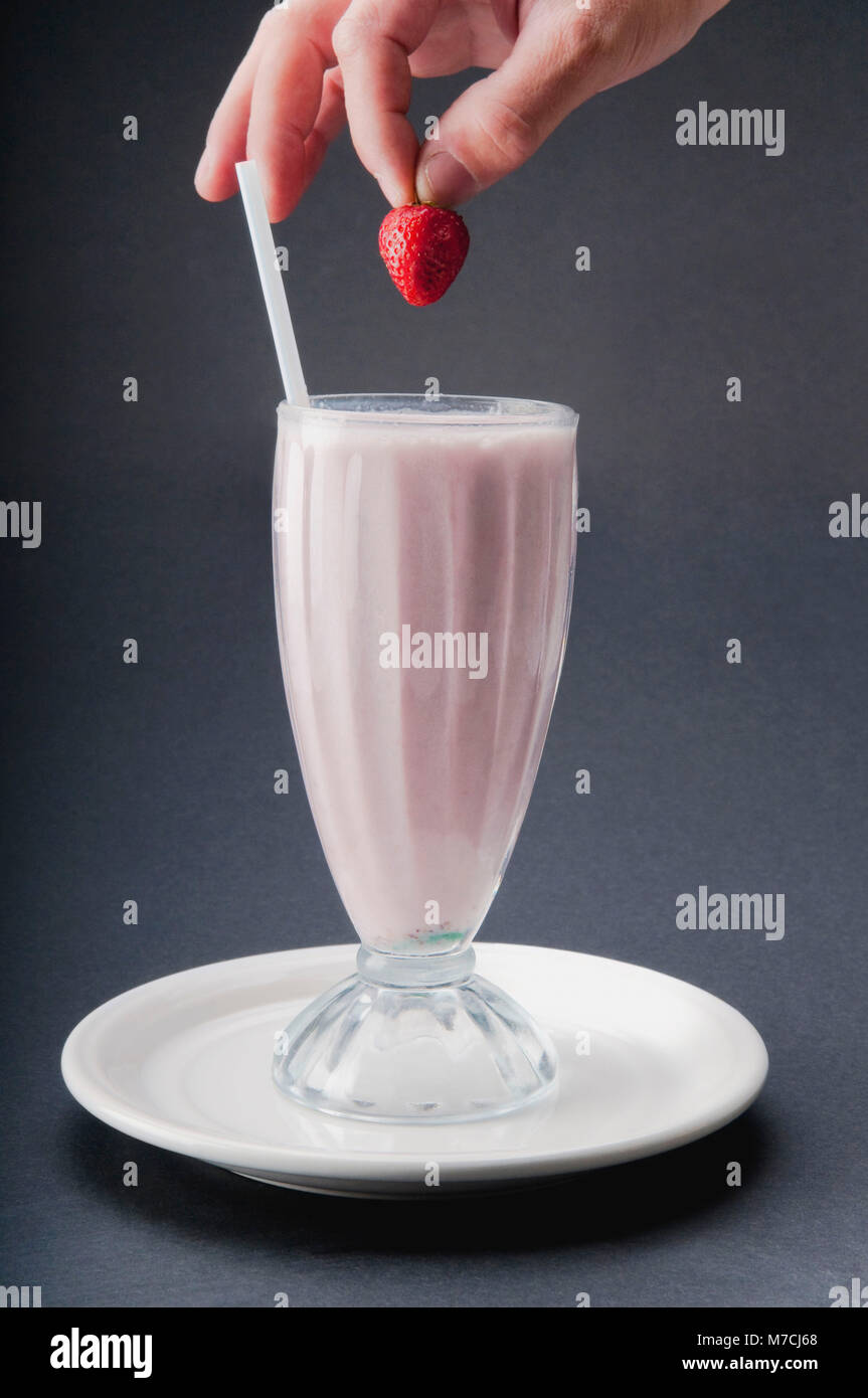 Close-up of a person's hand putting a strawberry in milkshake Stock ...